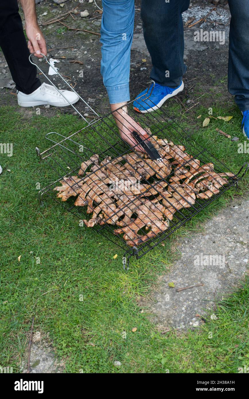 Unrecognizable men preparing lamb chops. Many chops in a cooking grid ...