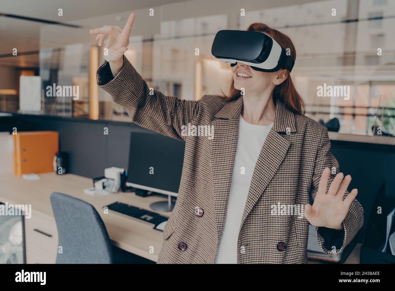 Happy female office worker in VR headset enjoying virtual reality game ...