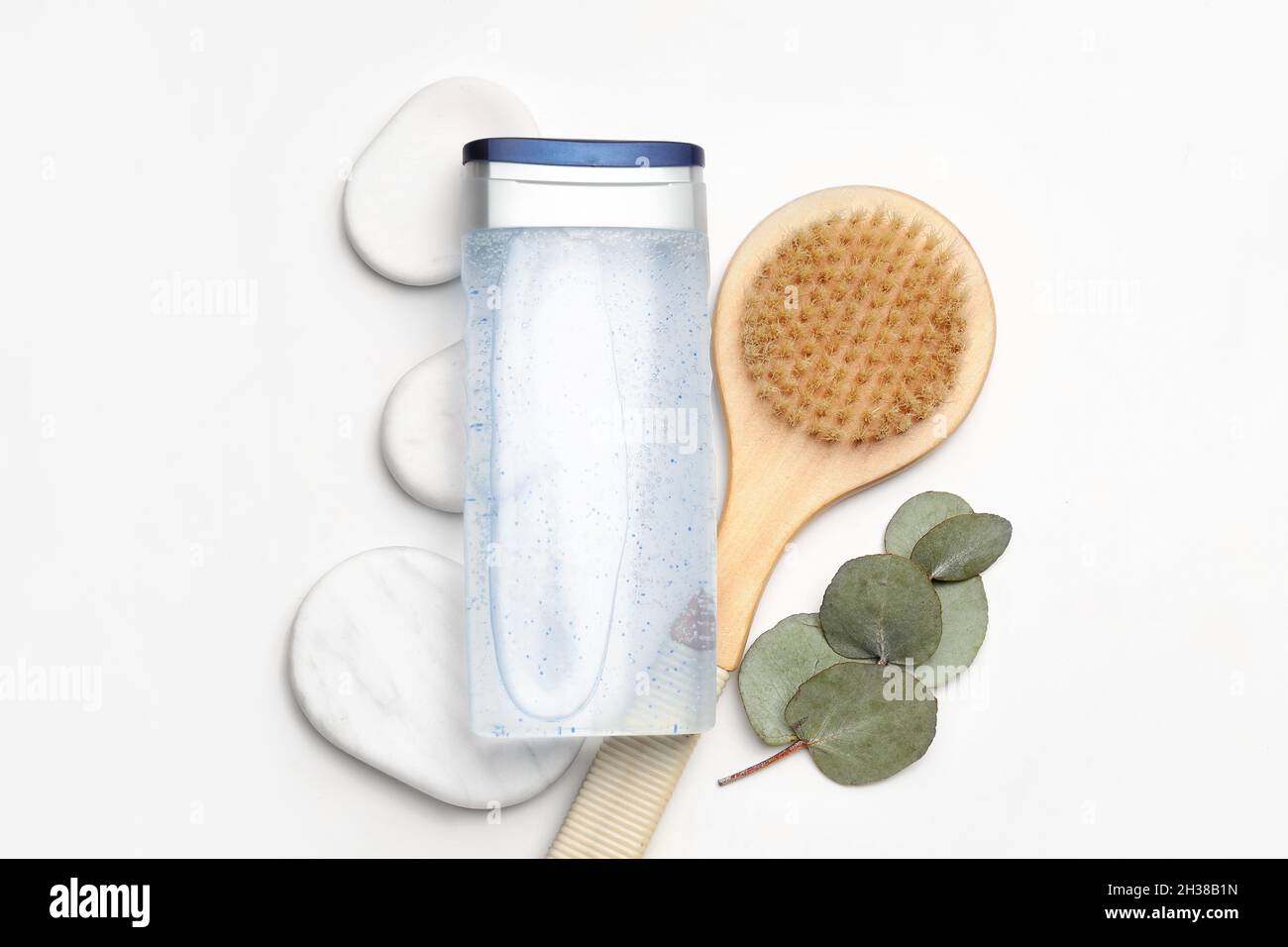 Bottle of shower gel, spa stones and massage brush on white background ...