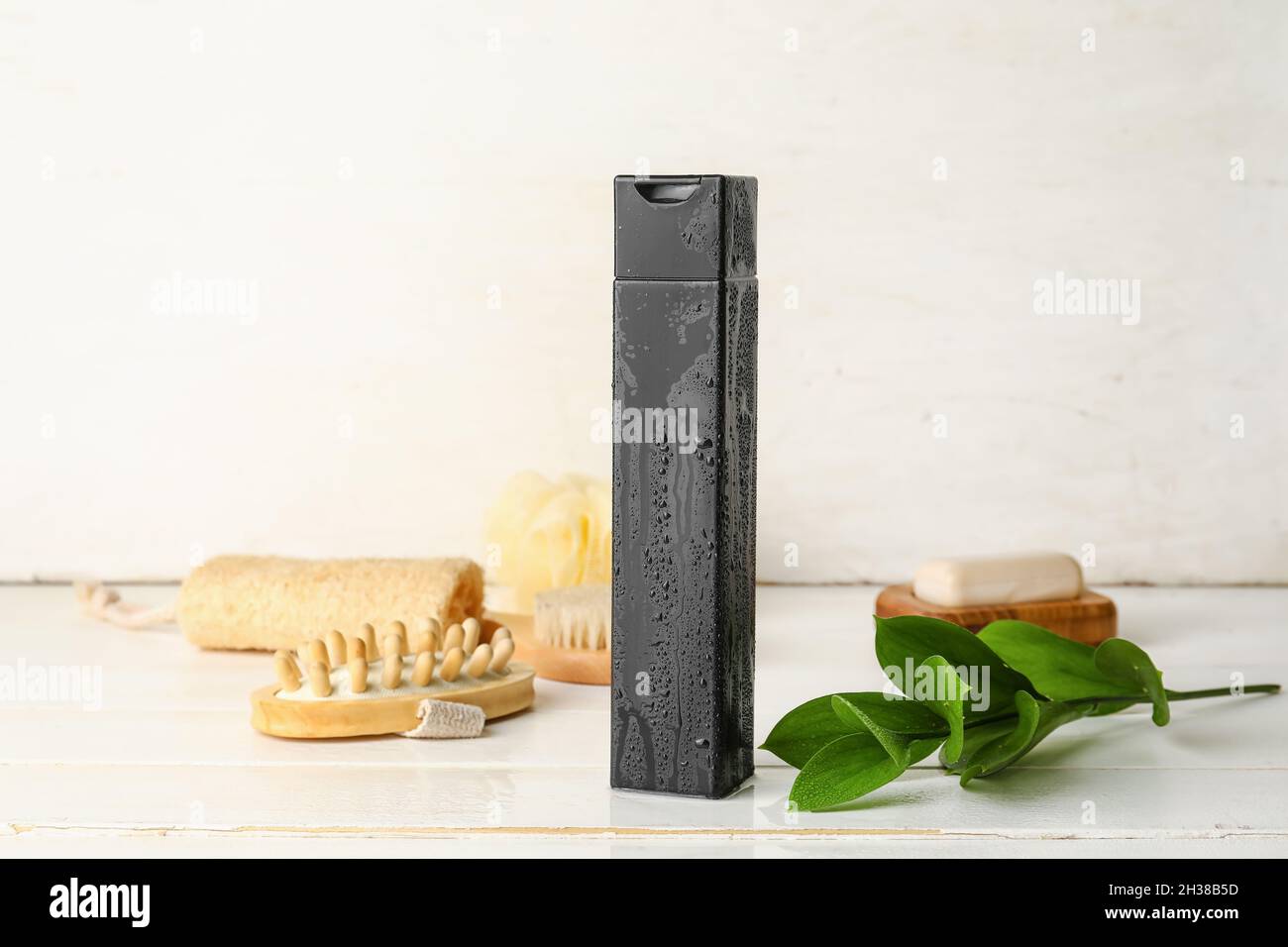Bottle of shower gel with water drops and bath supplies on light wooden ...