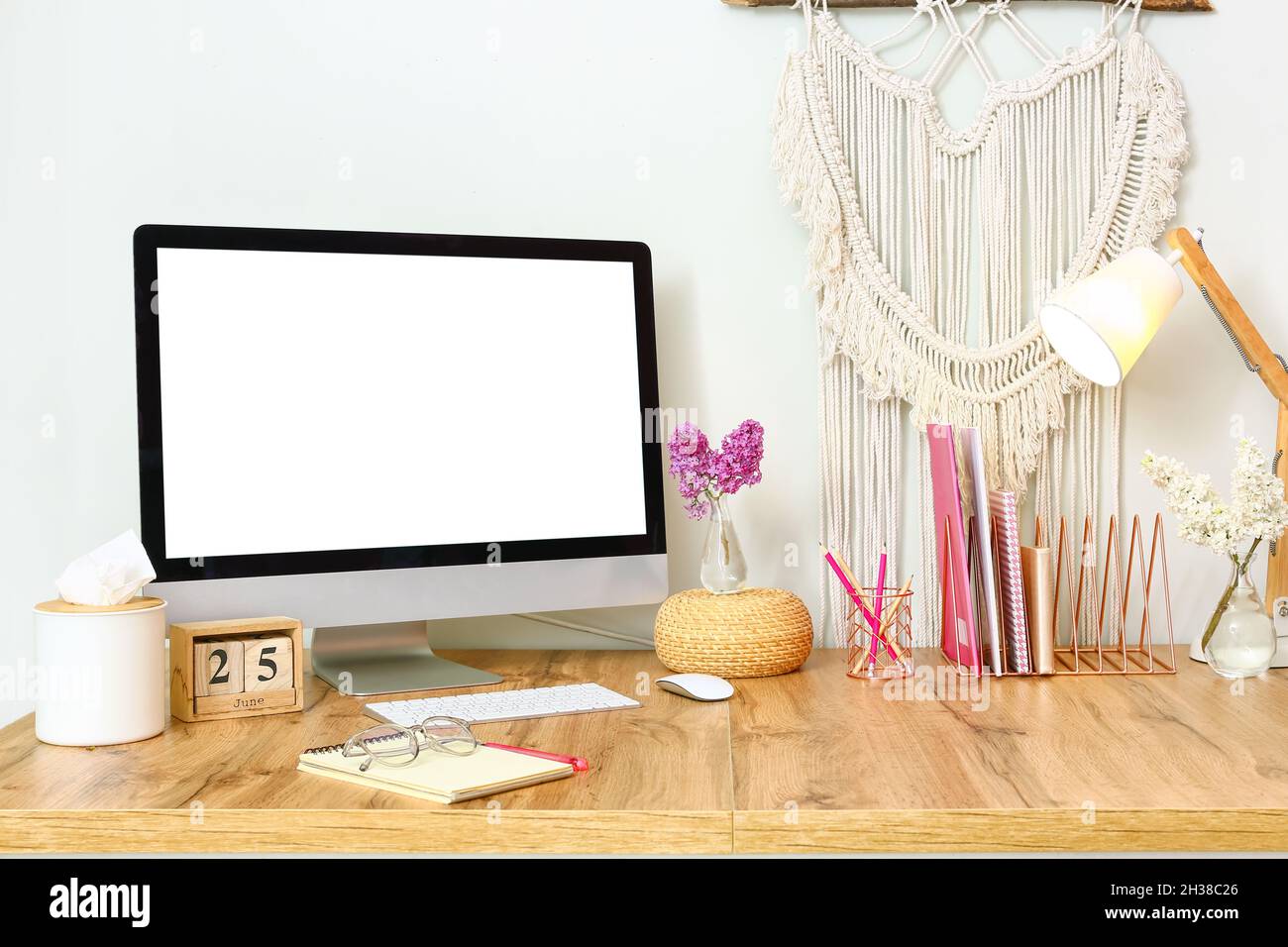 Computer with blank screen, stationery and lamp on desk near light wall ...