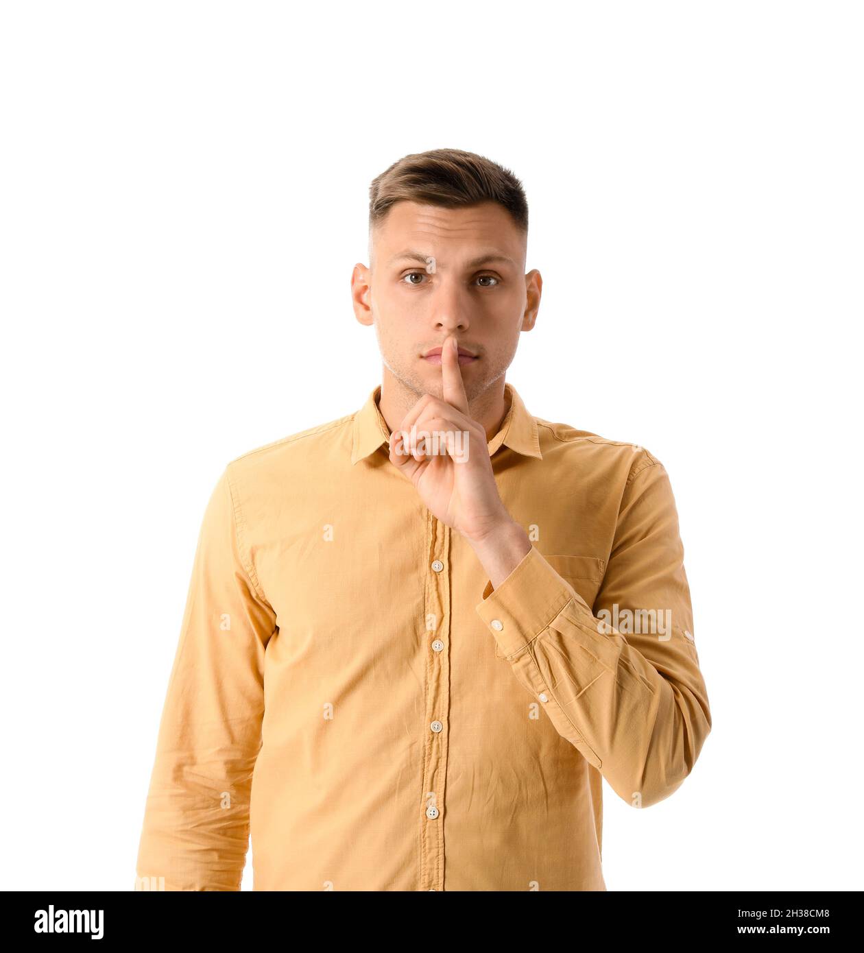 Young man showing silence gesture on white background Stock Photo - Alamy