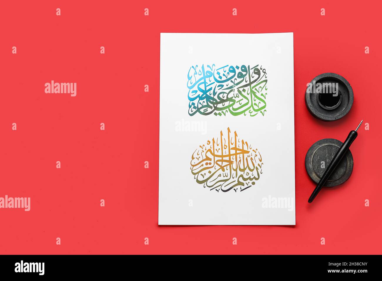 Paper with Arabic text and tools for calligraphy on color background ...