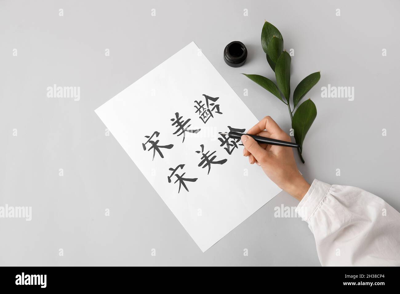 Asian calligraphist writing hieroglyphs on light background Stock Photo ...