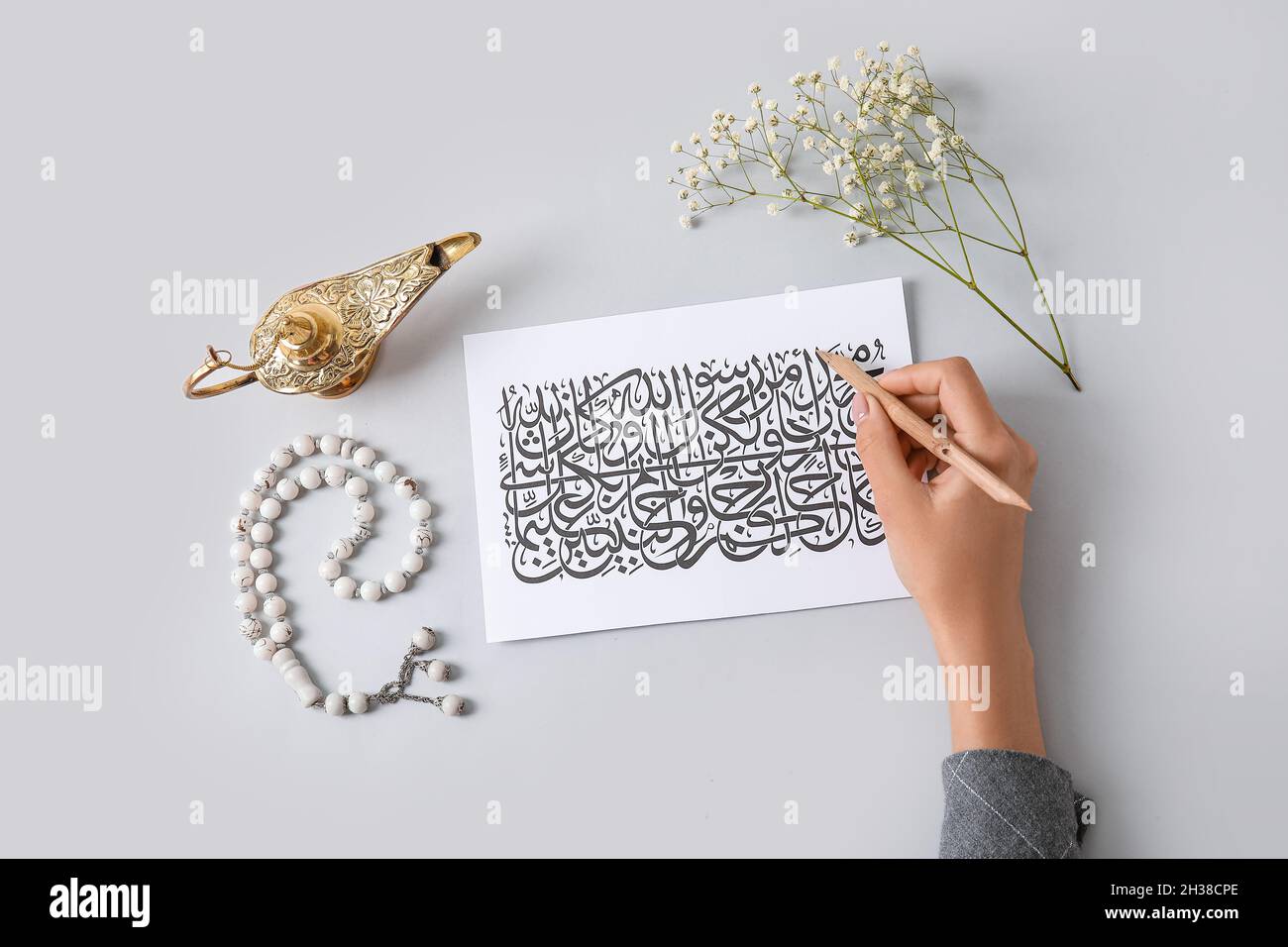 Arabic calligraphist writing on paper sheet against light background ...