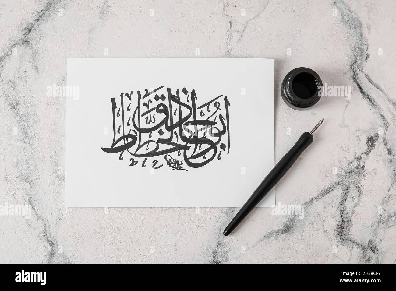 Paper with Arabic text and tools for calligraphy on light background ...
