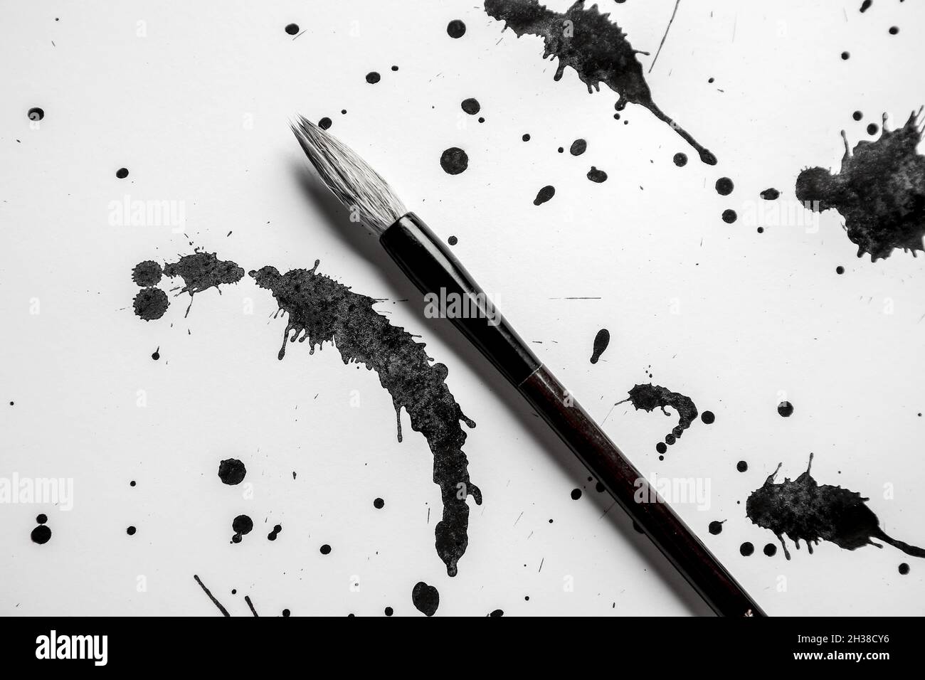 Ink spots and brush for calligraphy on white paper Stock Photo - Alamy