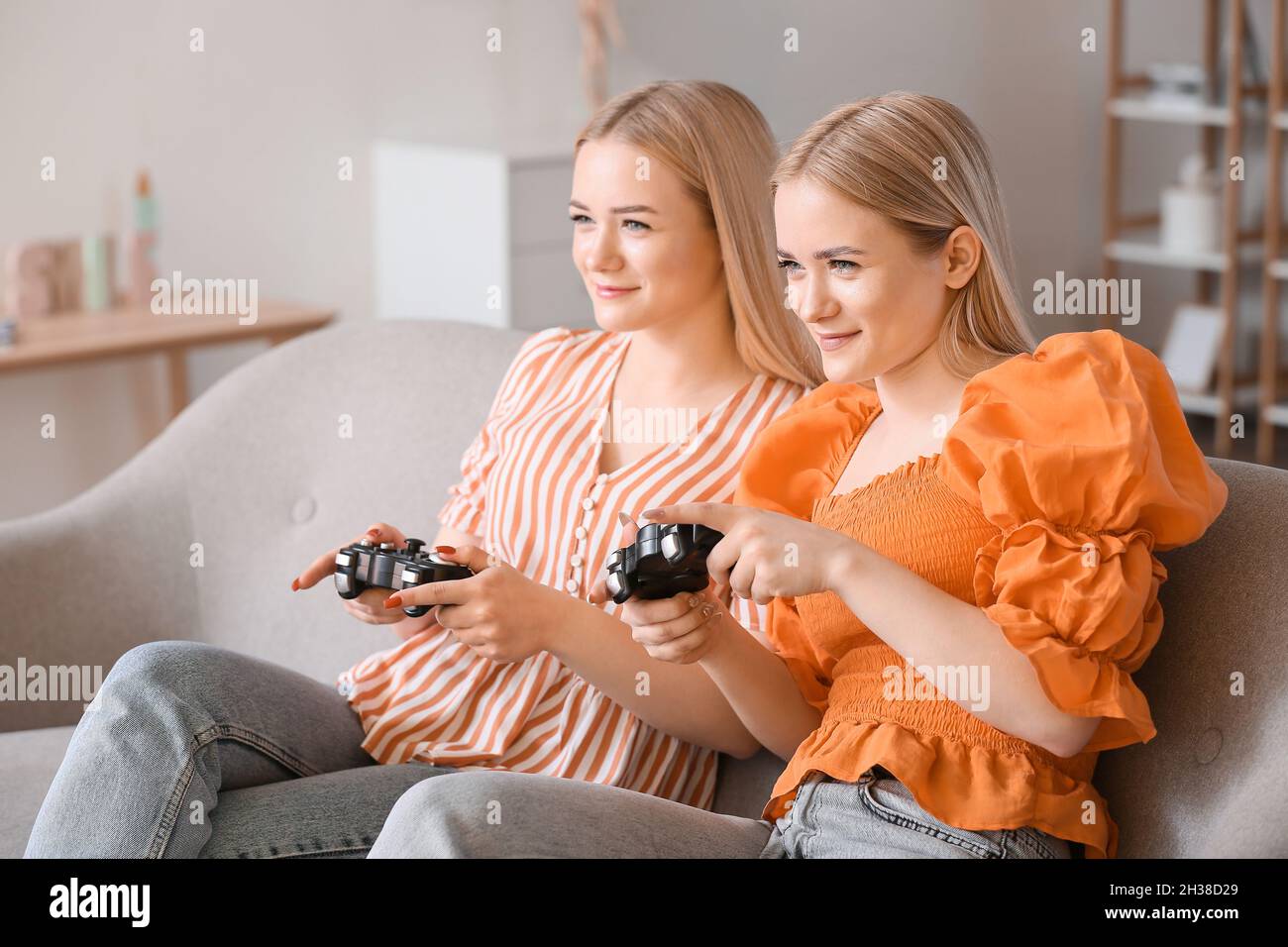 Young twin sisters playing video game at home Stock Photo - Alamy