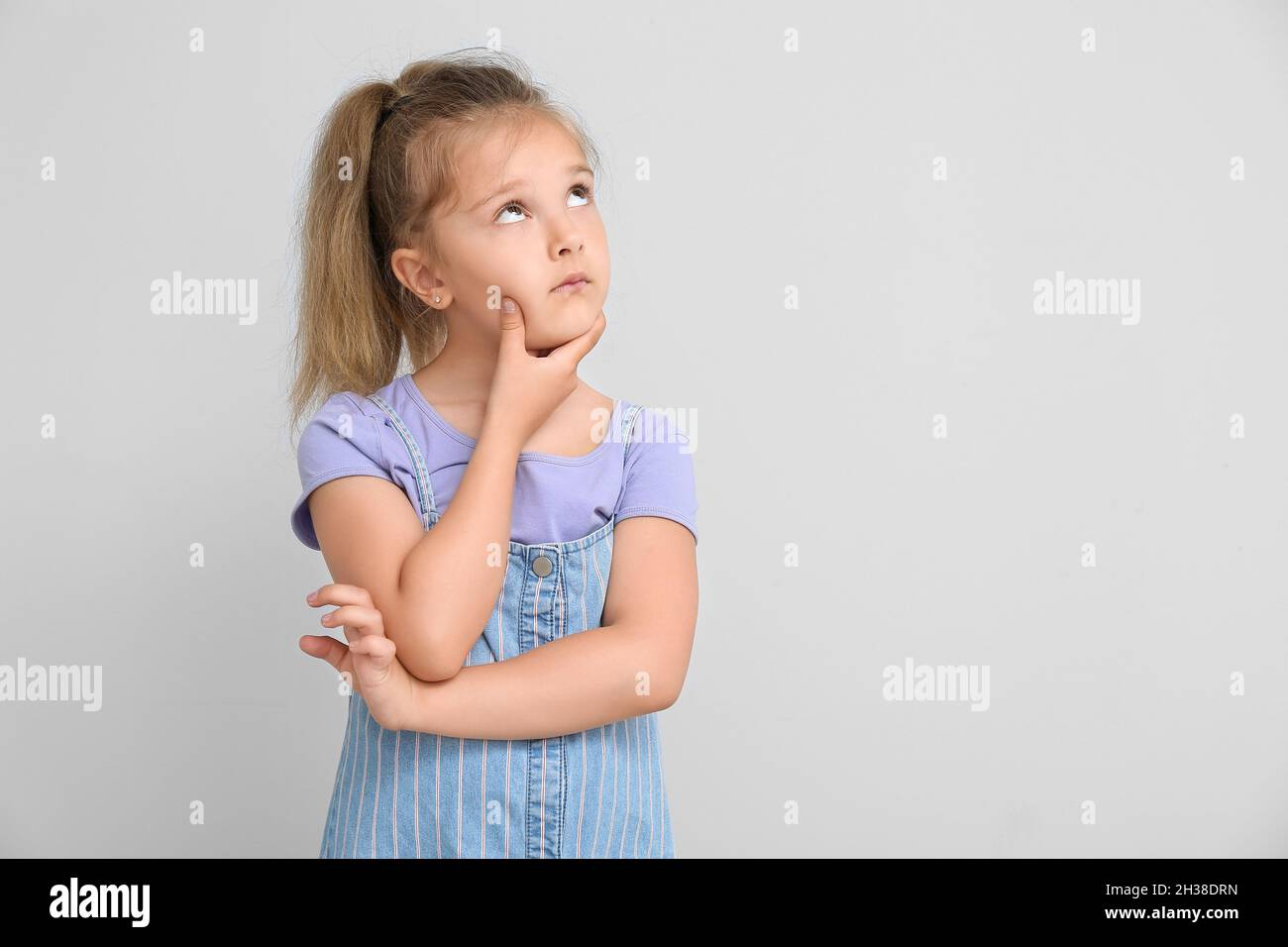 Thoughtful little girl on light background Stock Photo - Alamy