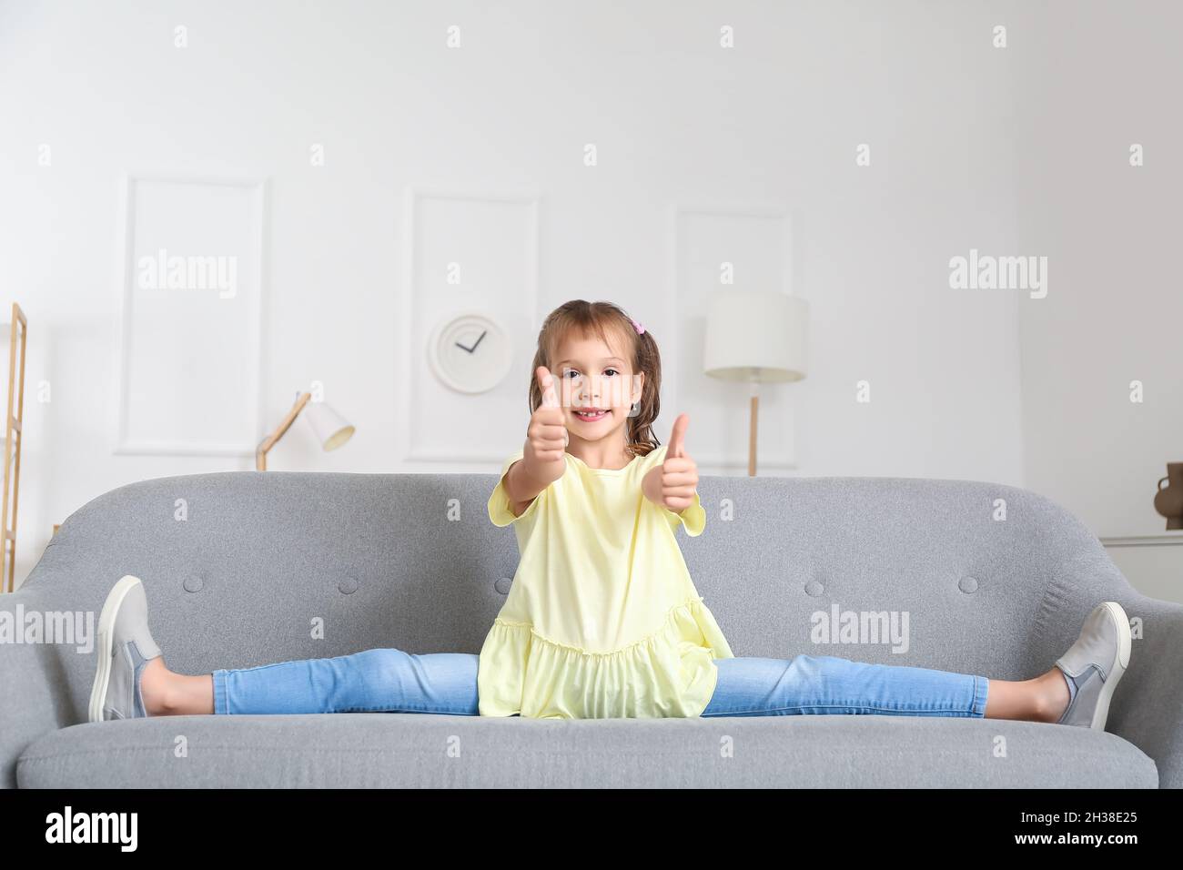 Little girl doing leg-split on sofa at home Stock Photo - Alamy