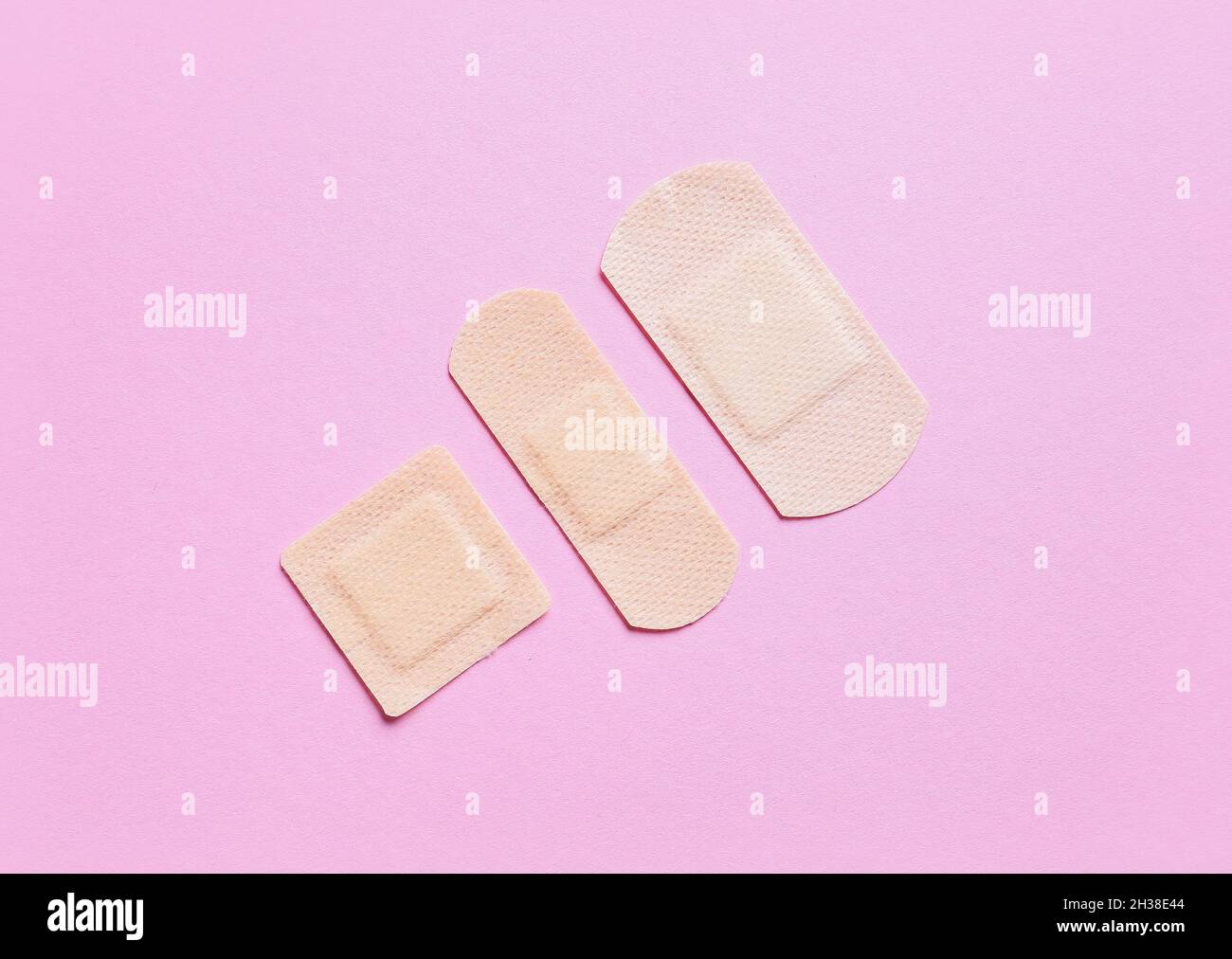 Different medical plasters on pink background Stock Photo - Alamy
