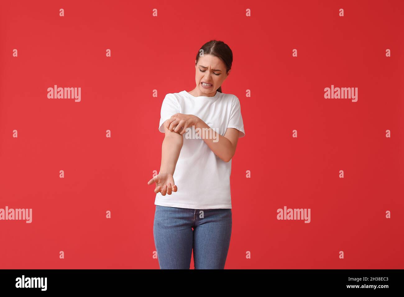 Young woman scratching herself on color background Stock Photo - Alamy