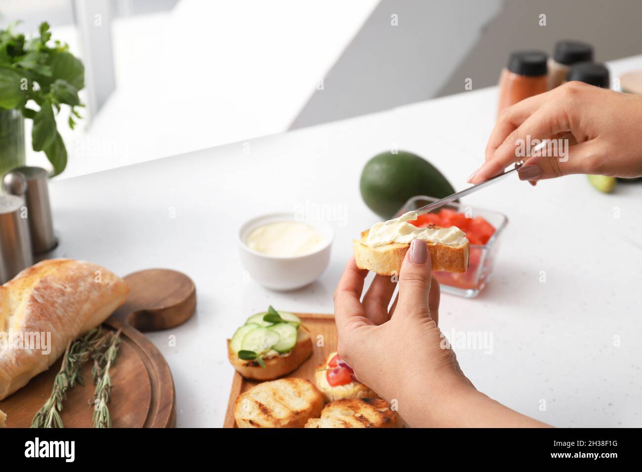 Woman spreading toast with dip at table in kitchen Stock Photo - Alamy