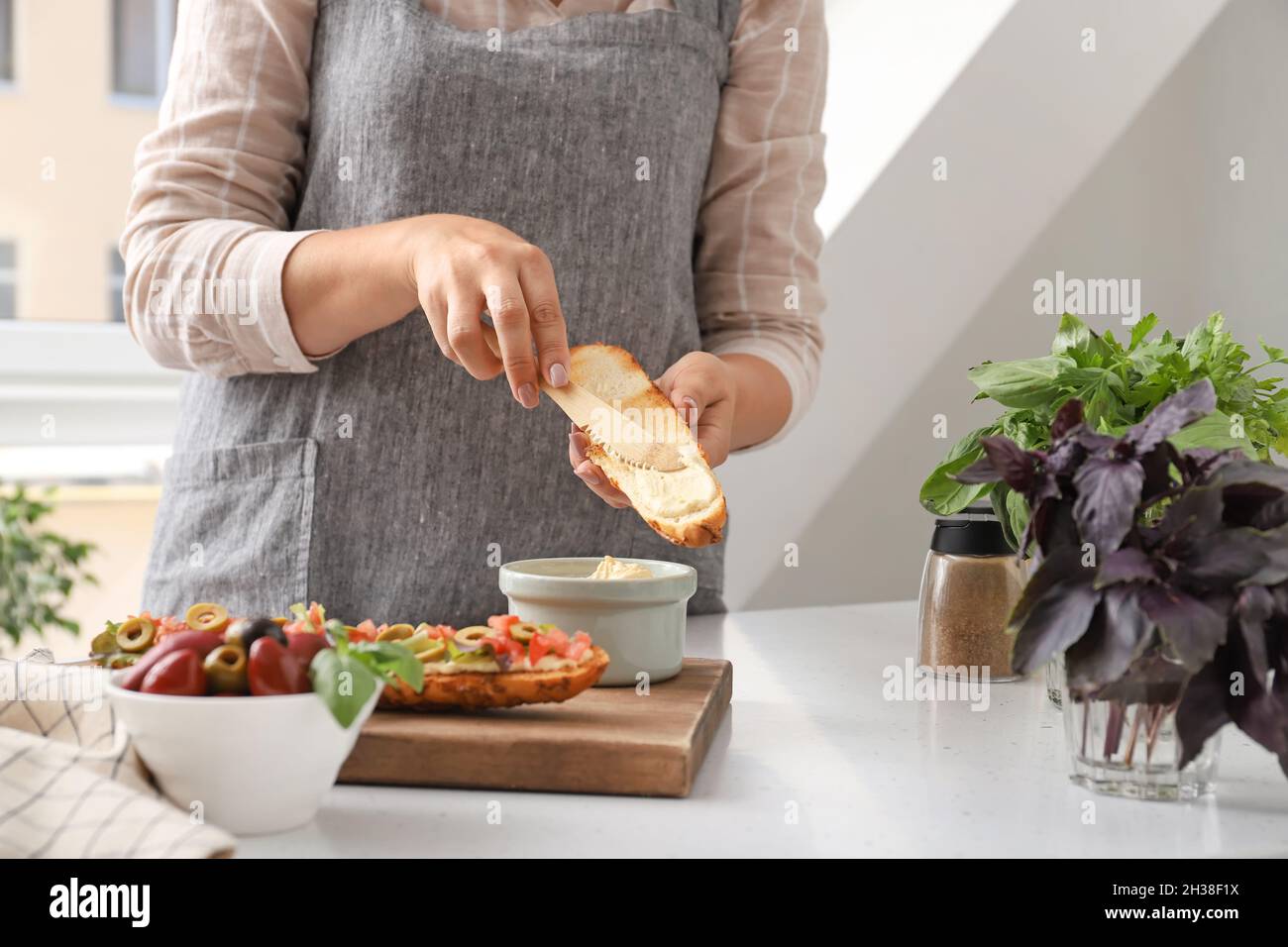 Woman spreading toast with dip at table in kitchen Stock Photo - Alamy