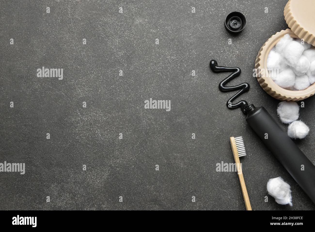 Black toothpaste with activated carbon, brush and cotton balls on dark ...