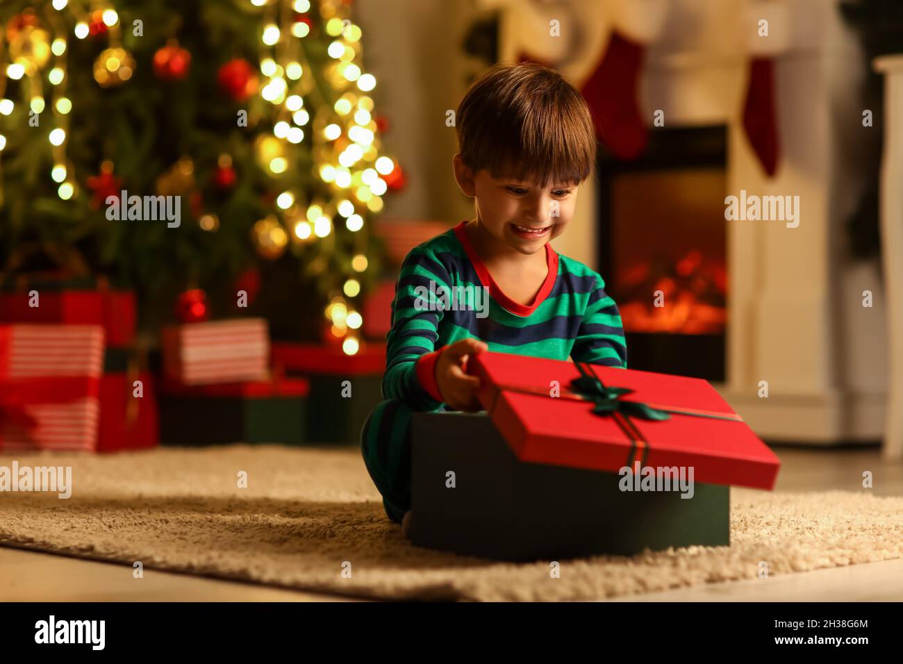 Cute little boy opening Christmas gift at home Stock Photo - Alamy