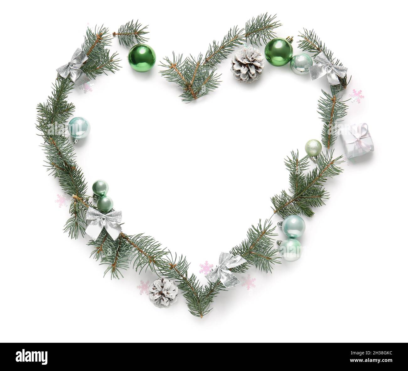 Heart made of coniferous branches and Christmas decorations on white ...