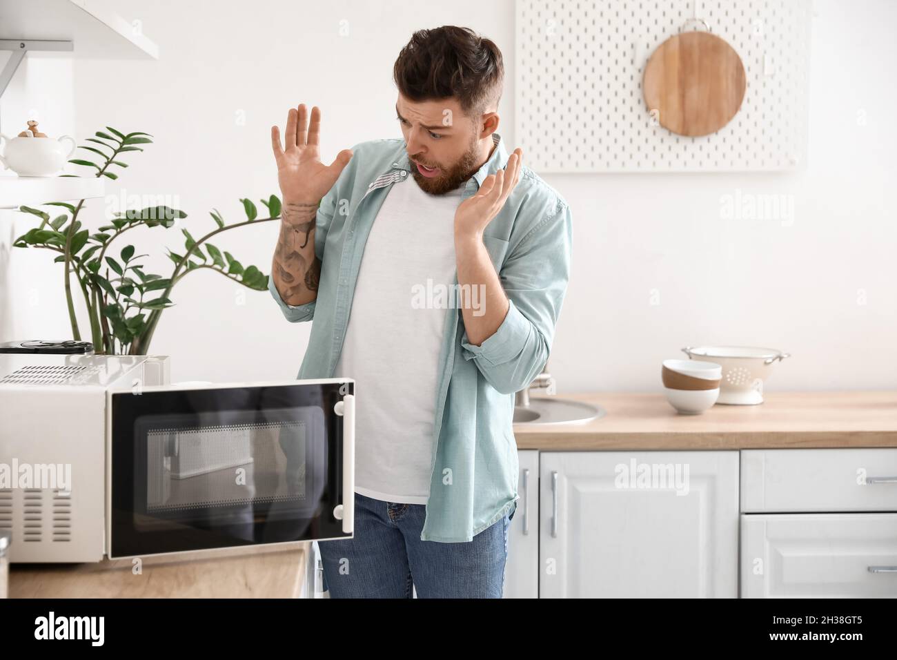 Shocked young man near microwave oven in kitchen Stock Photo - Alamy