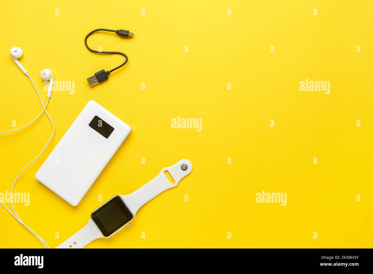 Modern power bank, smartwatch and earphones on yellow background Stock ...