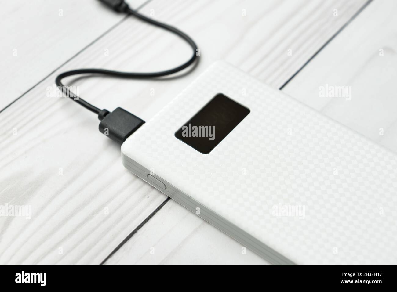 Modern power bank on white wooden background, closeup Stock Photo - Alamy