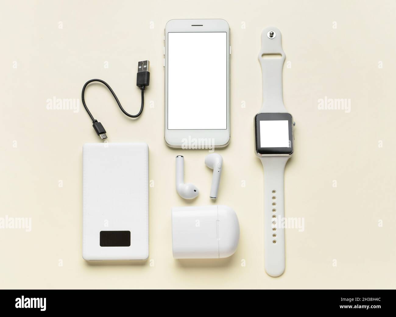 Modern power bank, smartwatch, earphones and mobile phone on beige ...
