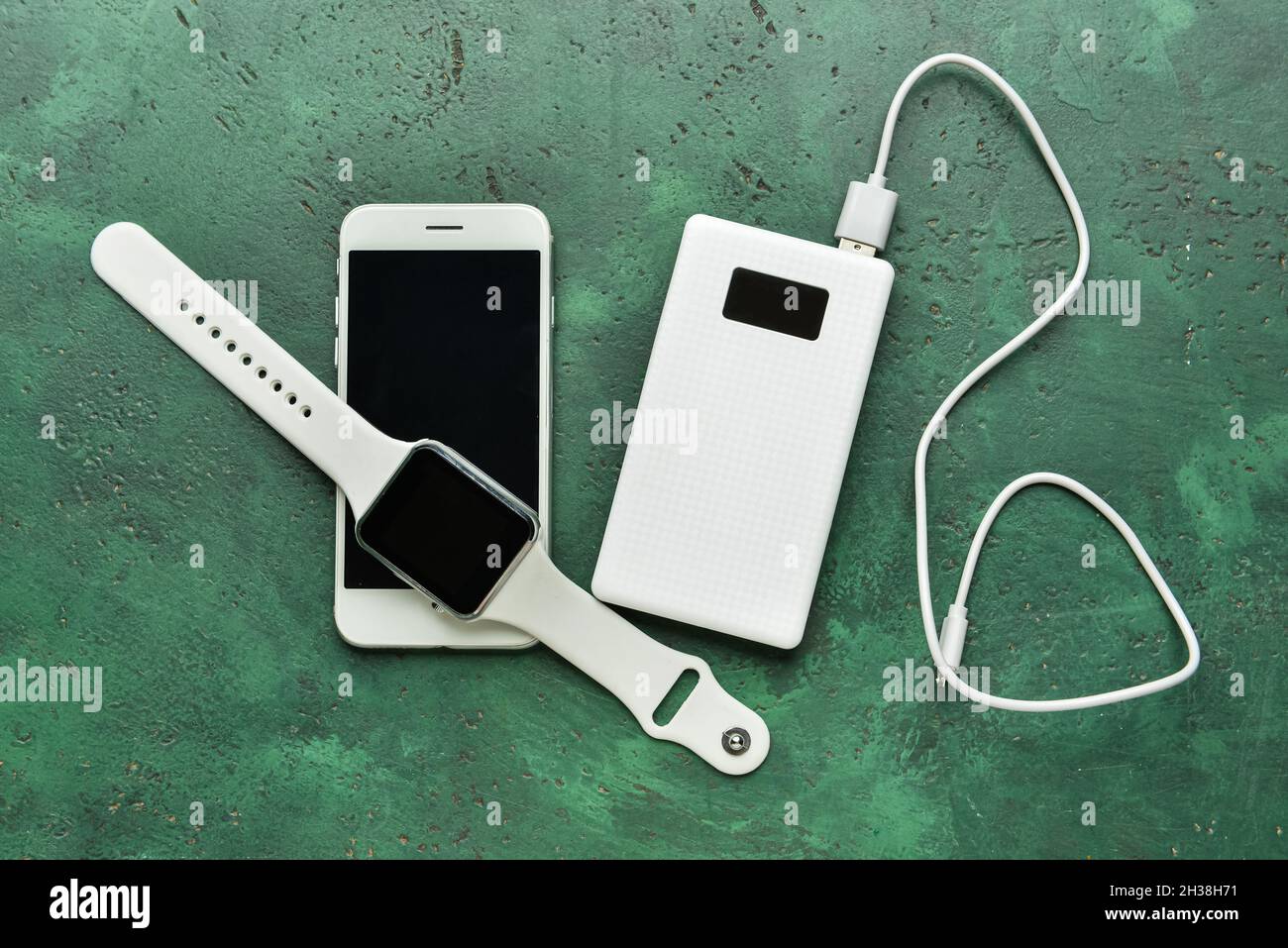 Modern power bank, smartwatch and mobile phone on green background ...