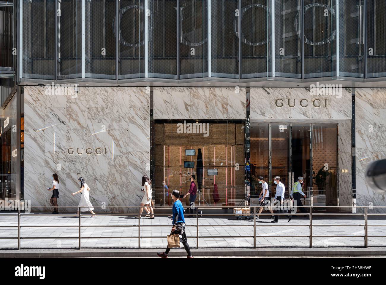 Pedestrians walk past the Italian luxury fashion brand Gucci logo and ...