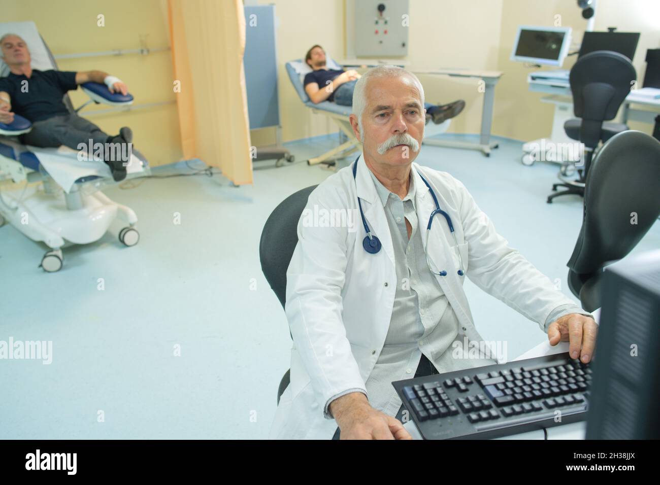 senior doctor looking at computer Stock Photo - Alamy