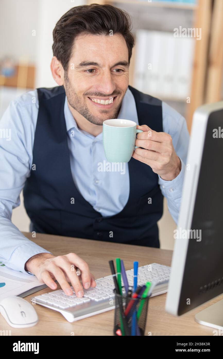 happy man drinking coffee in the office Stock Photo - Alamy