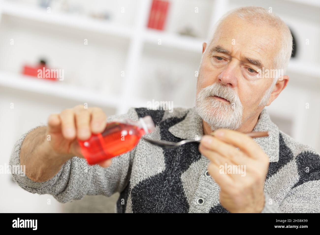 a mature man is pouring cough syrup in a spoon Stock Photo - Alamy