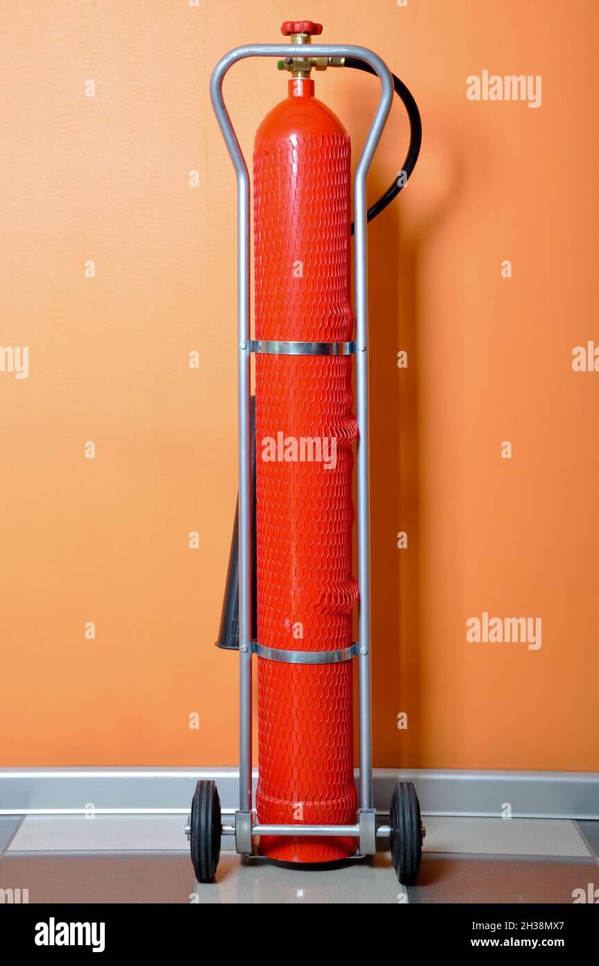 Red fire extinguisher, red fire tank, standing by the wall, ready to ...