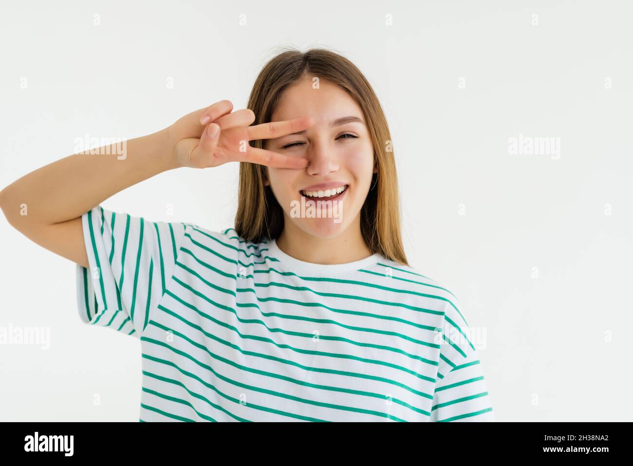 Happy young woman showing peace sign over grey background Stock Photo ...