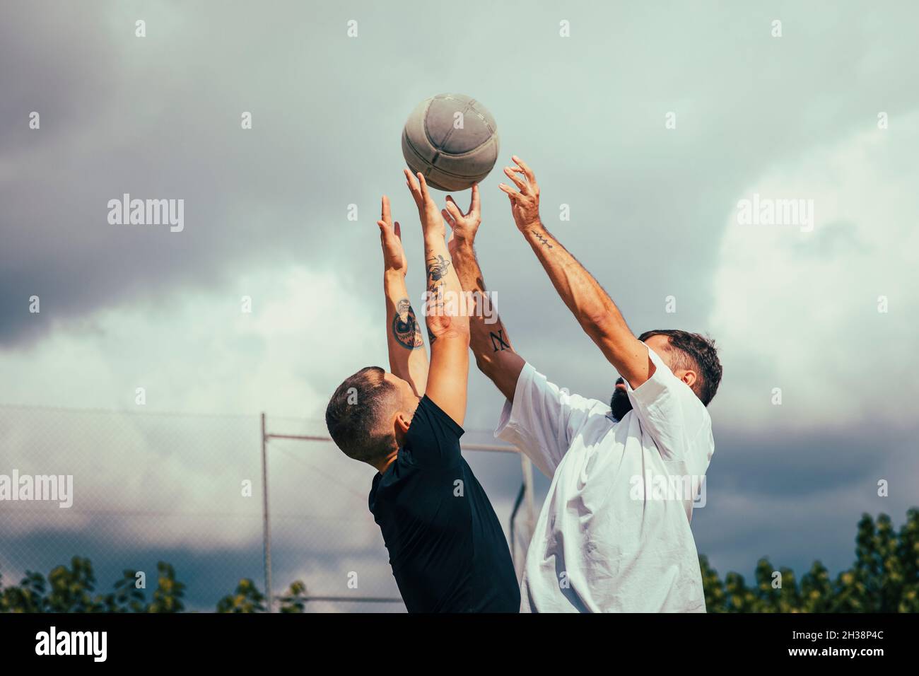 Two friends jumping in the air while fighting a basketball Stock Photo ...