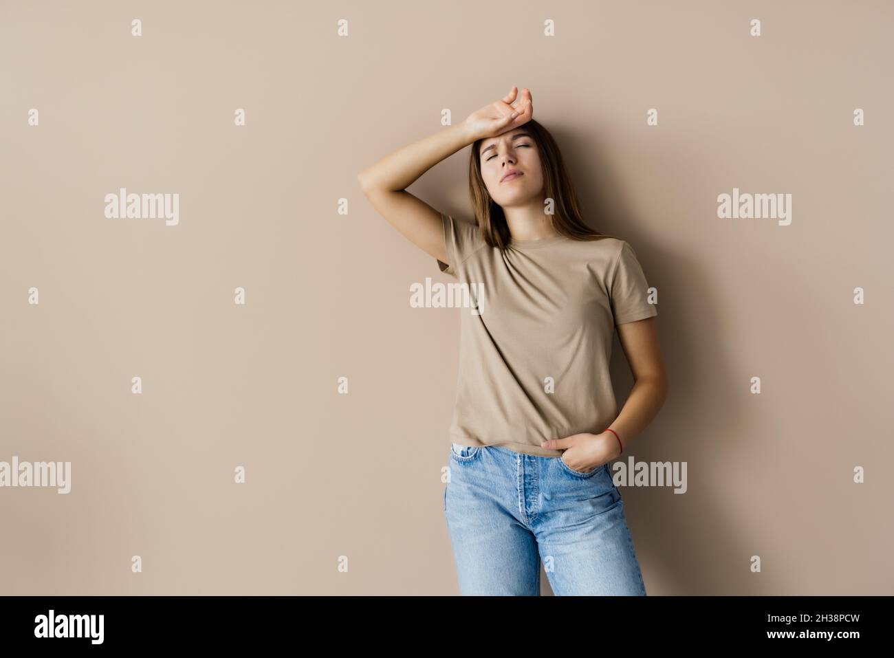 Beautiful exhausted woman standing isolated over beige background Stock ...