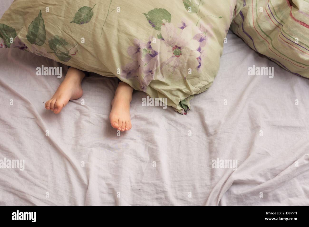 Feet of a small child sticking out from under a blanket with flo Stock ...
