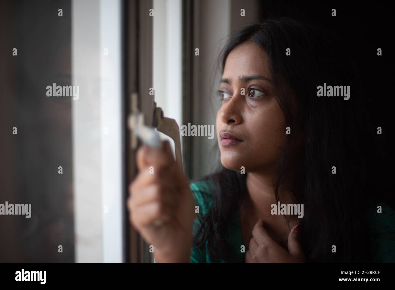 Young woman looking outside through window Stock Photo - Alamy