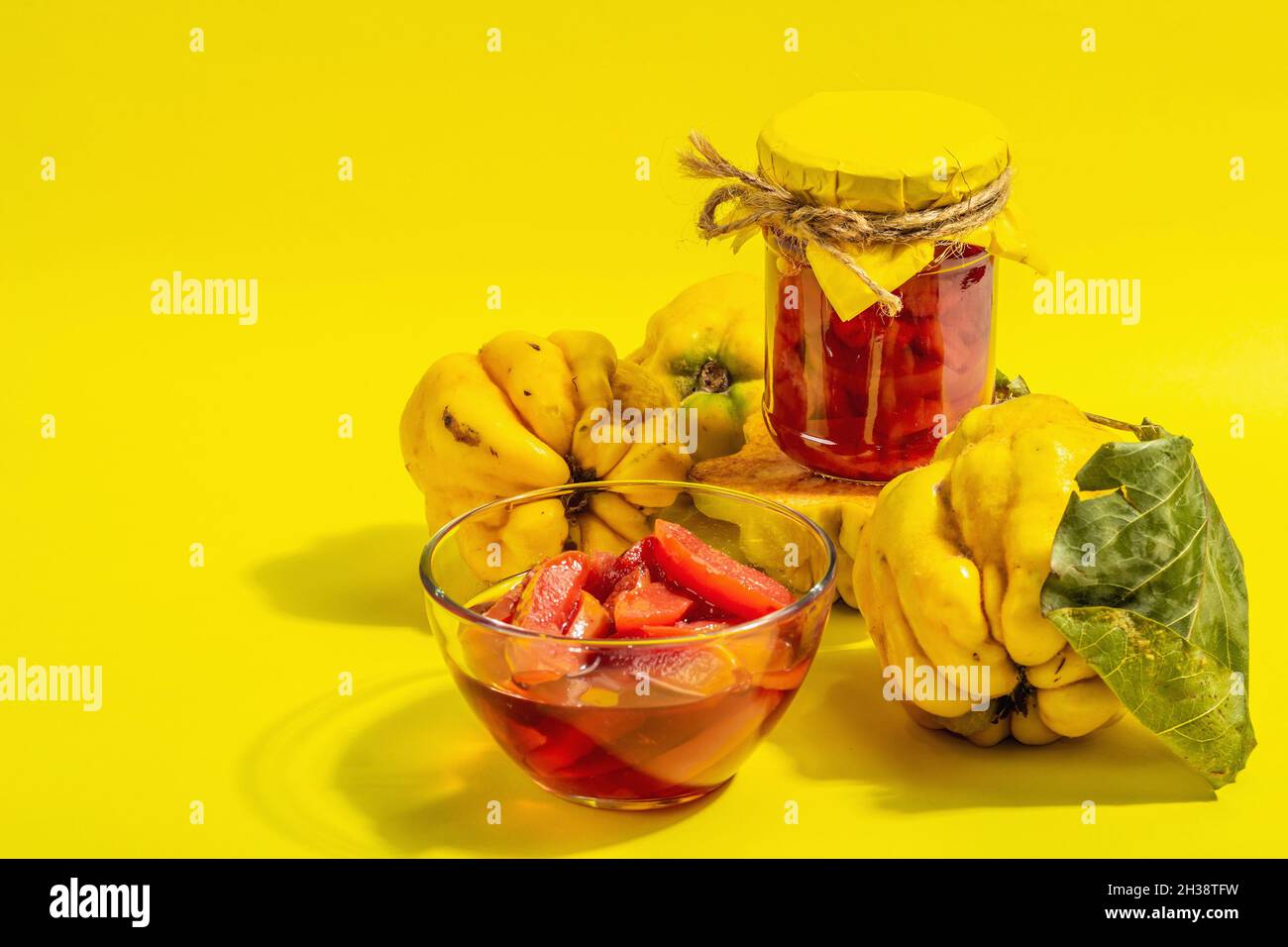 Ripe whole quince and sweet jam from it isolated on yellow background ...