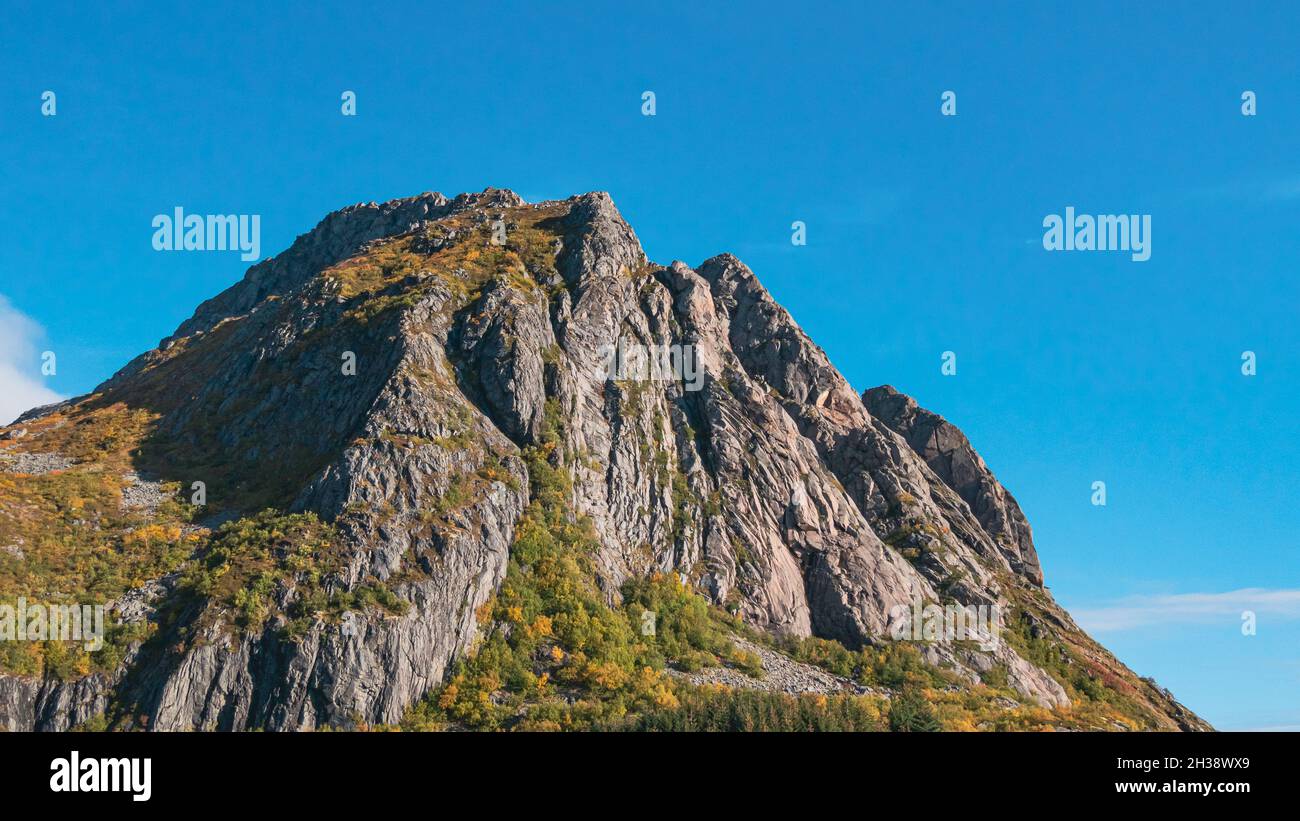 Low angle panoramic view of a high mountain peak covered with grass on ...