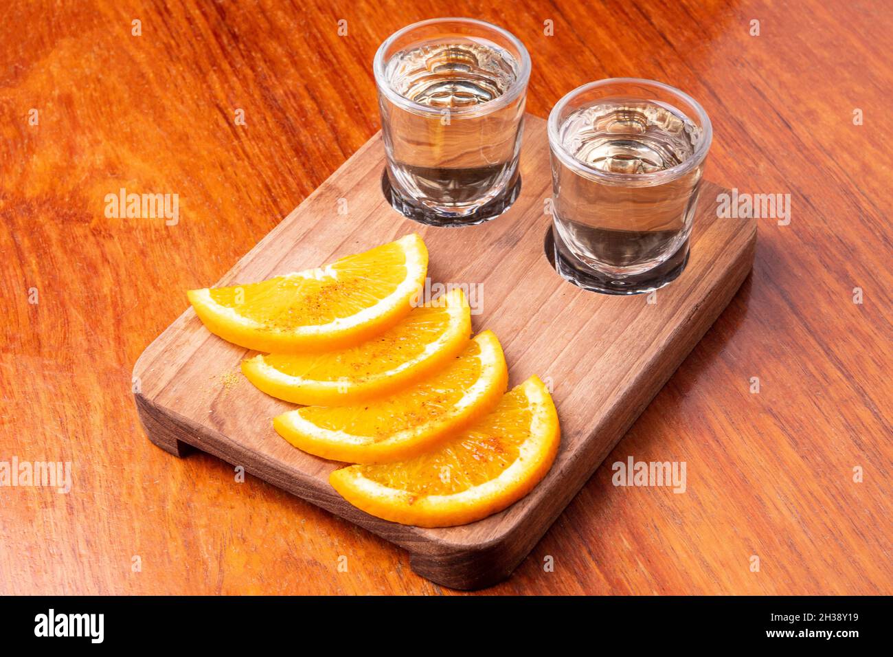 High-angle shot of a wooden tray with two alcohol shots and sliced ...