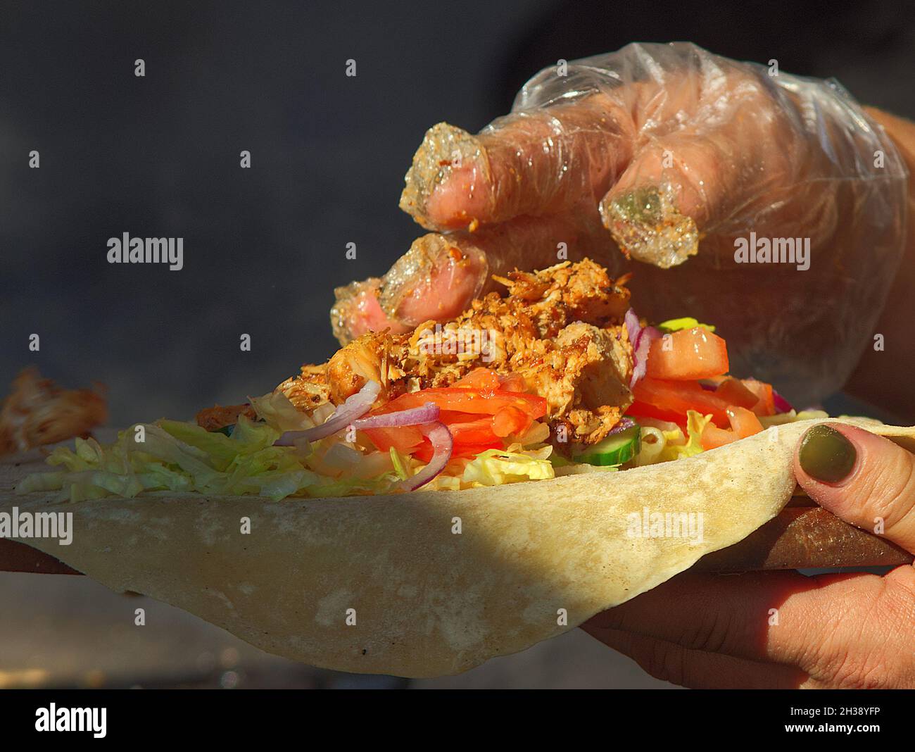 Production of fresh wraps in a stall at the farmers' market. Women's ...