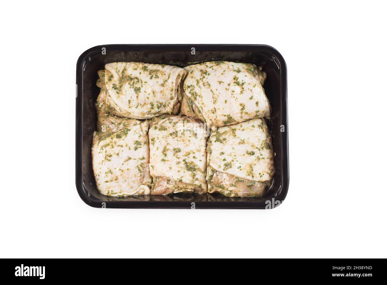 Raw marinated chicken thighs in sauce in a tray for a supermarket, on a ...