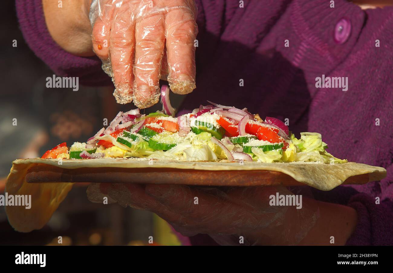 Production of fresh wraps in a stall at the farmers' market. Women's ...