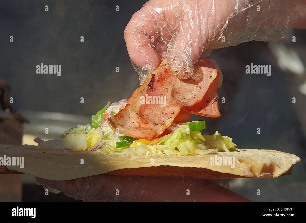 Production of fresh wraps in a stall at the farmers' market. Women's ...