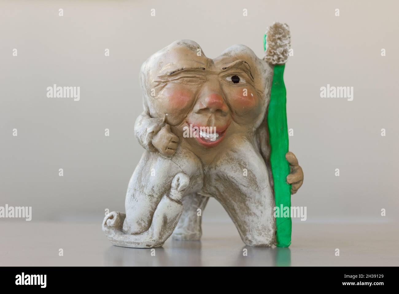 Isolated funny plaster tooth figure with smiling face shape holding a ...