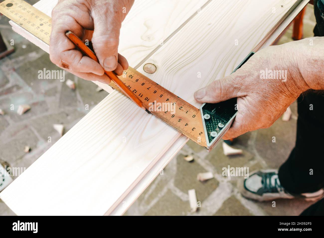 Close-up shot of craftsman hands measuring a wooden plank with angular ...