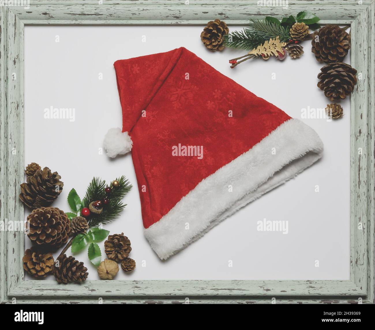 Red santa hat in a shabby wooden frame on a white background with fir ...