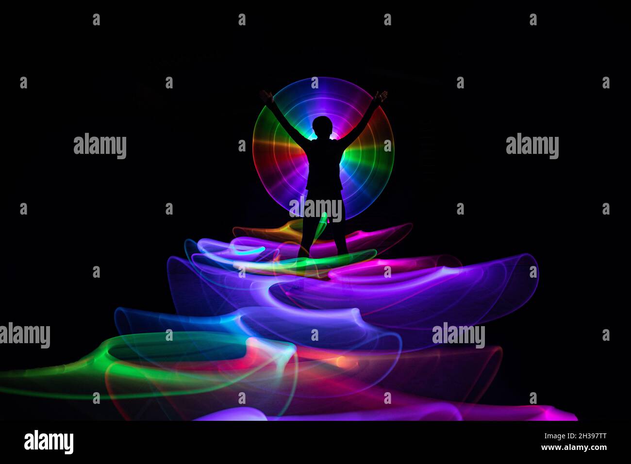 Silhouette of a person standing in front of a colorful circular prism ...