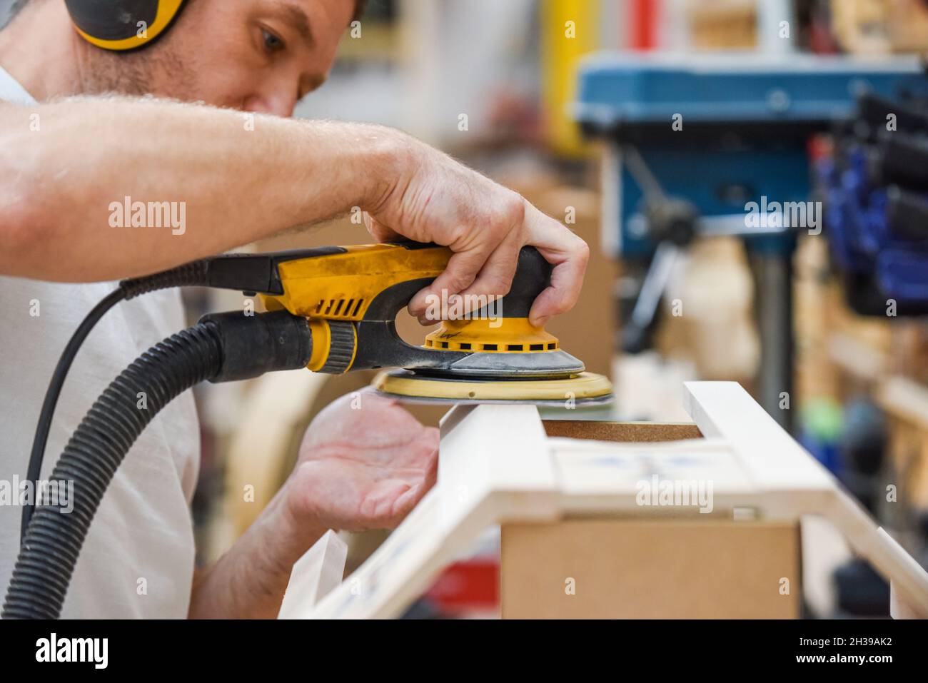 A man using a power tool electric sander to craft wood in the carpentry ...