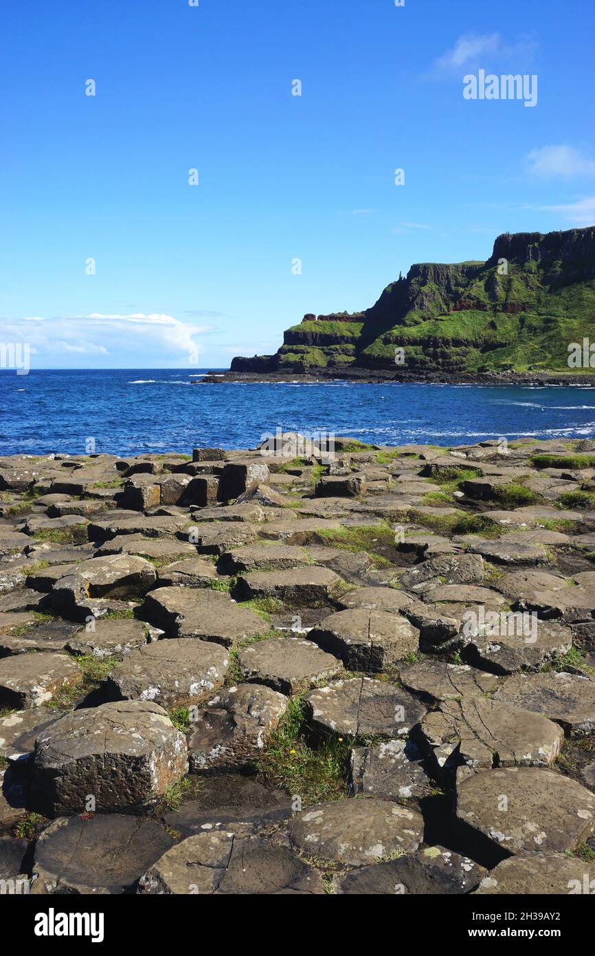 View of rugged green cliffs across blue water with natural volcanic ...