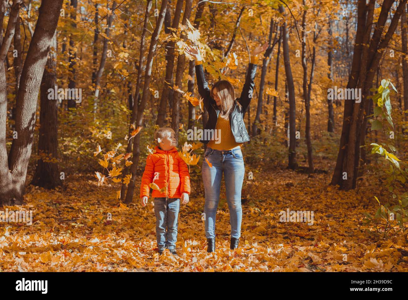 Single parent family playing with autumn leaves in park. Happy mom and ...